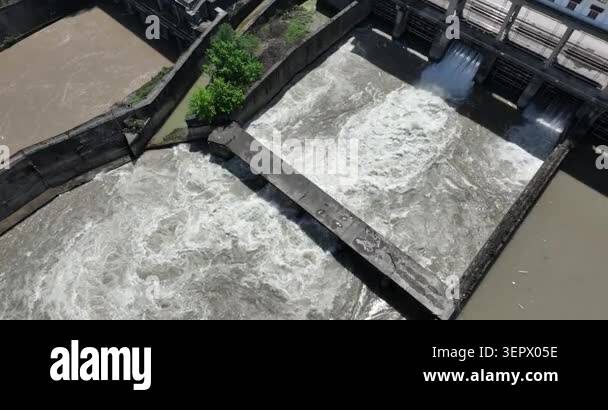 Aerial view of a dam with water flowing through the spillways and ...