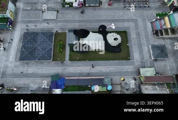 Aerial view of a giant inflatable panda lying on its back in a public ...