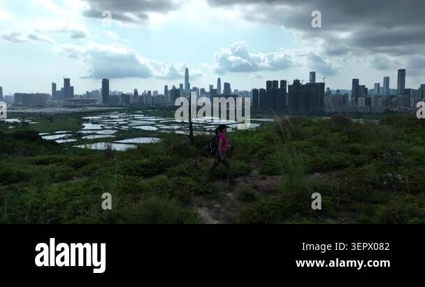 A lone woman with a backpack walks along a grassy hill overlooking a ...