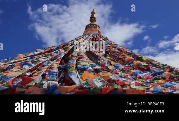 Colorful prayer flags flutter in the wind around a Buddhist stupa ...
