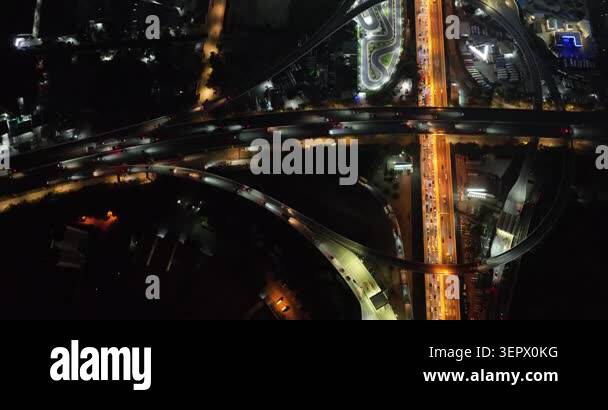Aerial night view of a busy highway interchange with cars driving on ...