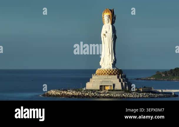 Wide shot of a large white statue of a deity standing on a man-made ...