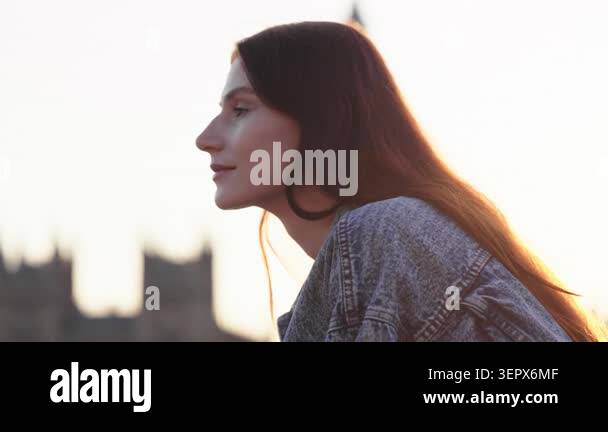 A beautiful redhead girl enjoys golden hour in London with Big Ben ...