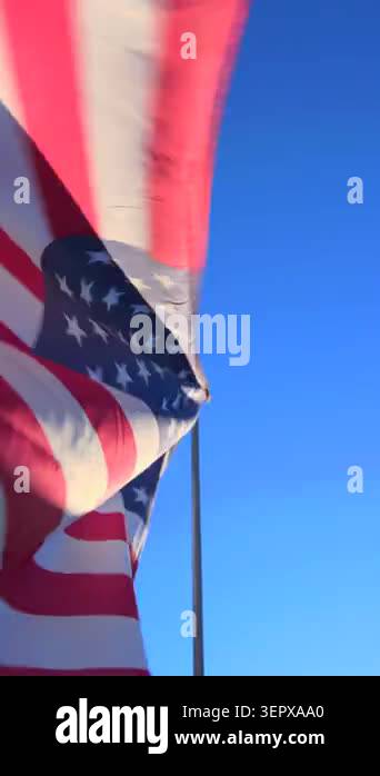 Vertical Screen: USA Flag waves gracefully in the wind during a ...