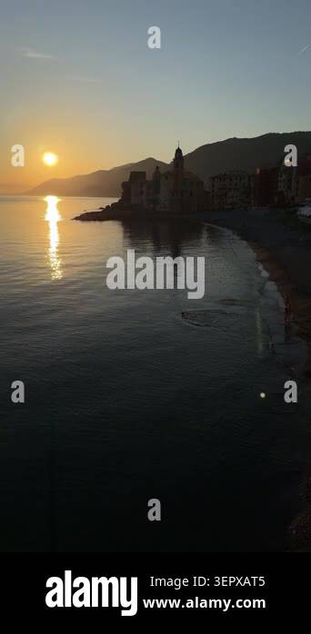 Bright sunlight rises over the coast of Camogli, Italy. The water ...
