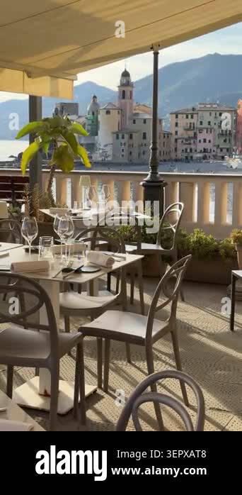 Guests sit at outdoor tables while enjoying drinks and food. The bright ...