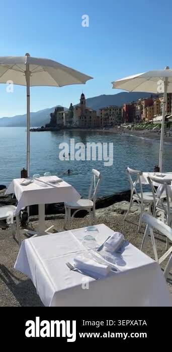 A table set for lunch overlooks the water in Camogli. People relax ...