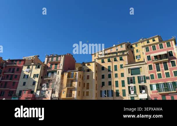 In Camogli, Italy, bright buildings line the shore under a clear blue ...