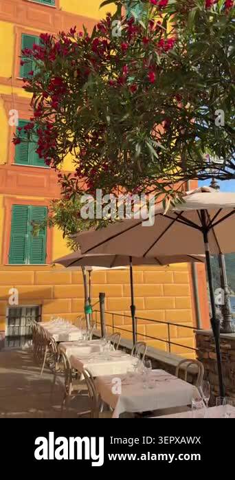 People are sitting at tables under umbrellas outside a restaurant in ...