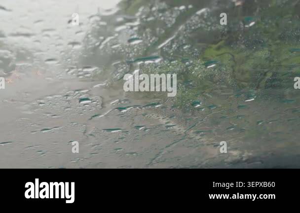Heavy summer rain falling on a car's windshield while driving on a wet ...