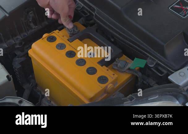 Male hands connecting the terminals on a new yellow car battery inside ...