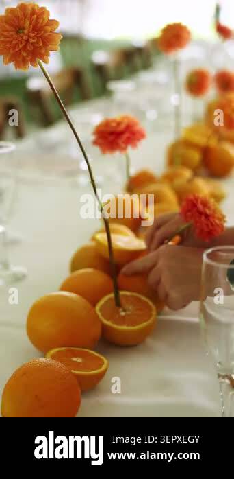 Vertical video showing close-up of hands arranging oranges and flowers ...