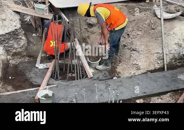 Construction workers in safety vests and hard hats manually dig and ...