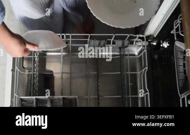 Top view of woman loading dirty plates into a dishwasher during a home ...