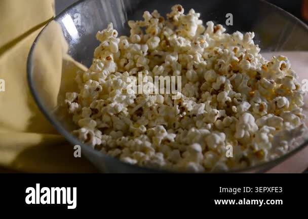 Close up of a bowl filled with popcorn while a hand repeatedly reaches ...