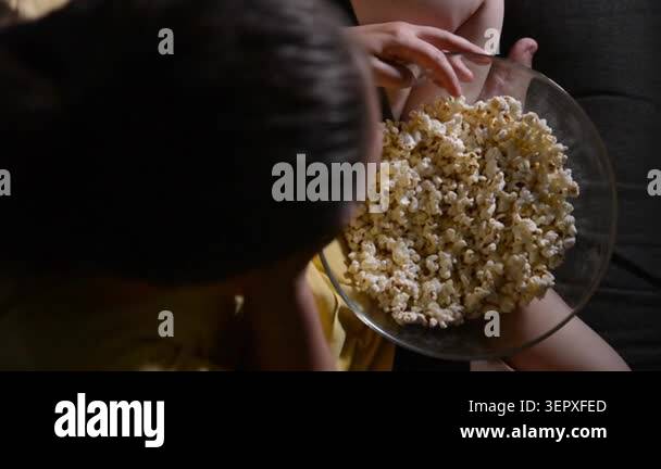 Top view of a young woman actively eating popcorn from a bowl. Focus ...