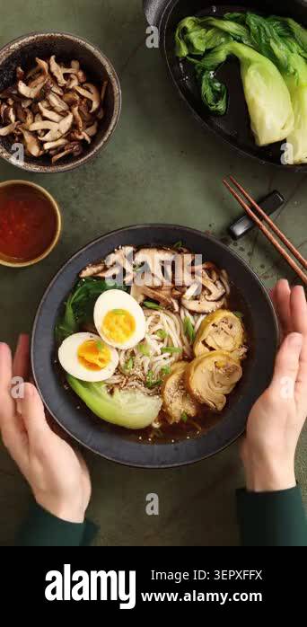 Top view vertical video of hands rotating a finished ramen bowl for ...