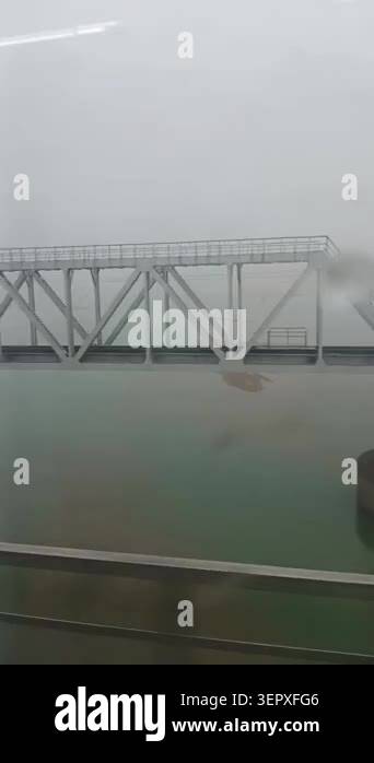 Moving train POV of a distant concrete bridge over a broad sandbank ...