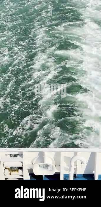 Vertical video tracking shot shows wake being churned up from a ferry ...