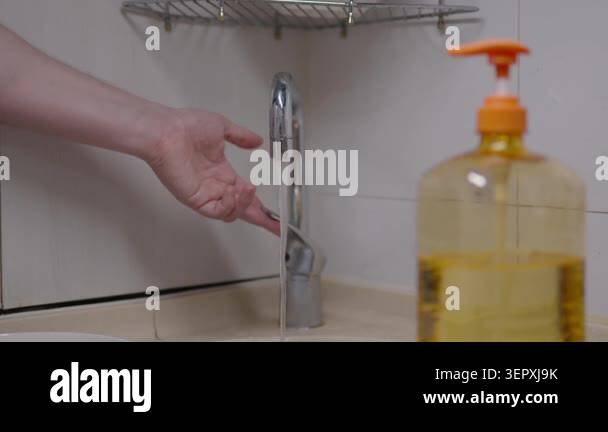 Person hand reaching for a chrome faucet, turning on the water near a ...