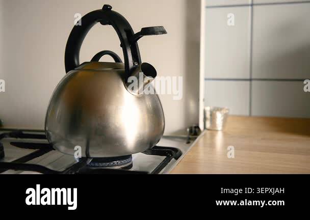 Classic metal kettle boiling on a home kitchen gas stove with visible ...