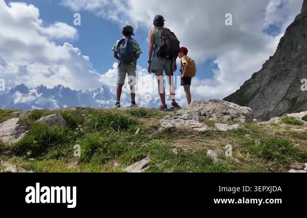 A woman and two children stand on a rocky mountain ridge, looking out ...