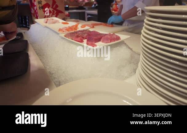 Chefs hands in gloves slicing and arranging fresh raw fish and seafood ...