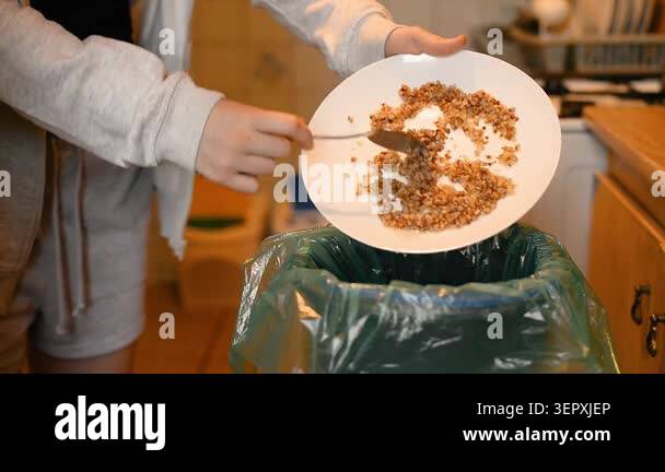 Teenage girl scraping and discarding remaining food leftovers into ...