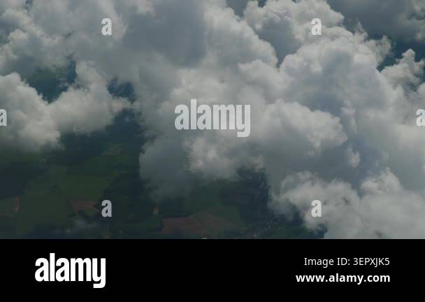 Aerial view from an airplane window looking down at clouds and green ...