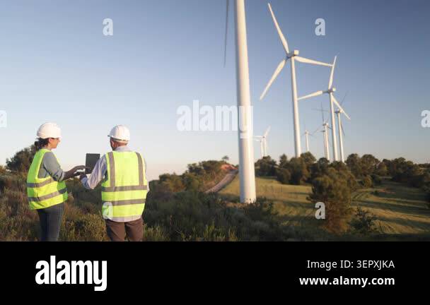 Two engineers in hard hats and high-visibility vests are standing in a ...