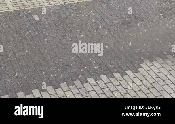 raindrops falling on paving stones during heavy rain with water puddles ...