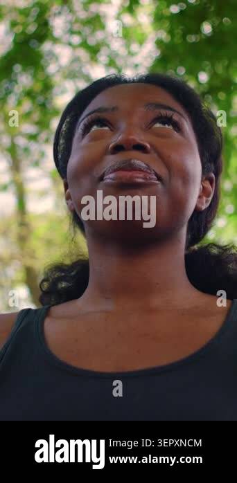 Young African American woman lifts open arms with gentle smile while ...