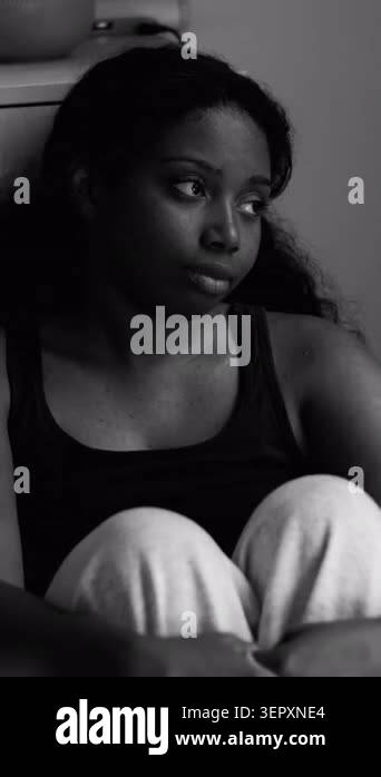 Young African American woman sits on the floor with a tense expression ...