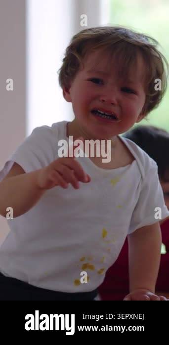 Upset young child expresses frustration during a meal while an older ...