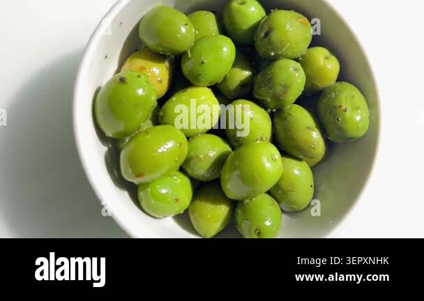 Top down view of marinated whole green olives with herbs and spices in ...
