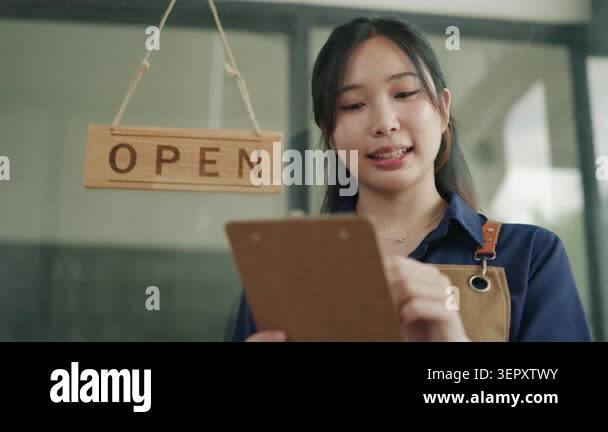 Woman holding clipboard near open sign of cafe Stock Video Footage - Alamy