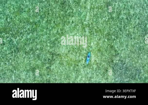 Unique aerial top down perspective of a lone kayaker paddling a blue ...