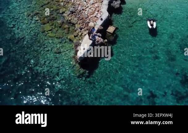 Aerial view of a rocky pier with unrecognizable people standing at the ...