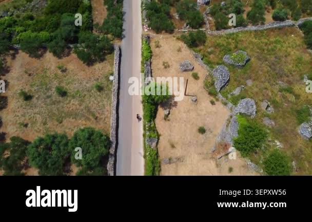 Aerial top down view of a person cycling on a paved road through the ...