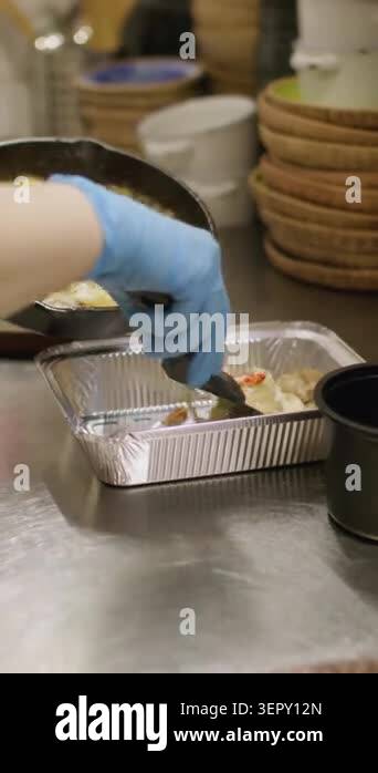 Vertical video. Serving food. Preparing takeaway meal. Chef in gloves ...