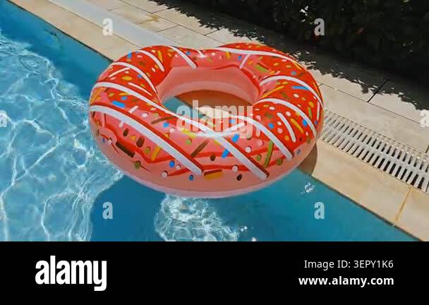 Colorful donut inflatable ring floating near the edge of a clear blue ...