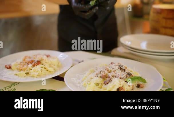 Garnishing dish. Preparing pasta. Gloved chef hand adding fresh green ...