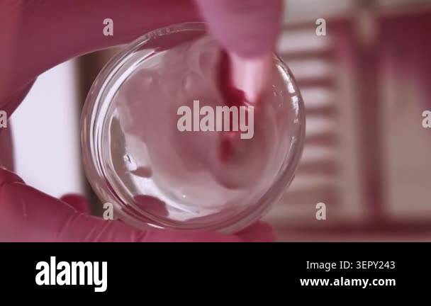 Skincare cream stirring. Beauty treatment. Beautician hands in pink ...