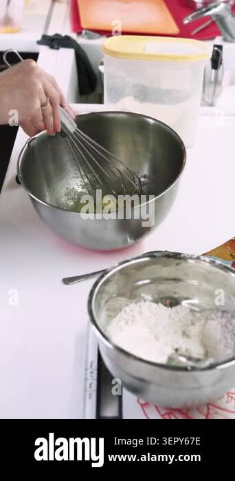 Vertical video. Kitchen process. Mixing dough. Baker hand whisking egg ...