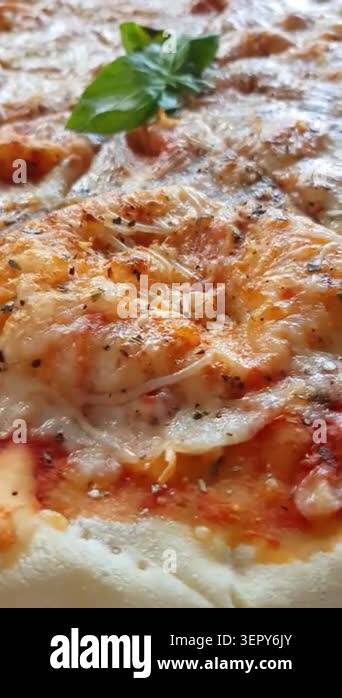 Close-up vertical video of a tasty margherita pizza with melted cheese ...