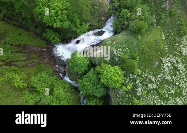 Aerial drone footage captures a flowing river cascading over rocks ...