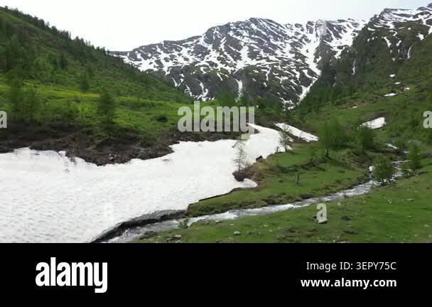 Aerial view of a winding stream flowing through a green mountain valley ...