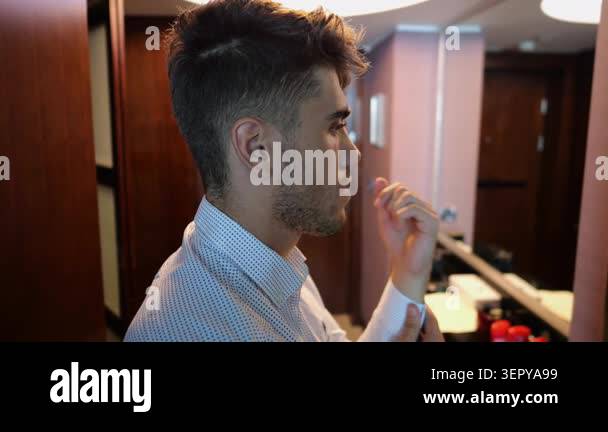 Young businessman adjusting shirt cuffs in front of mirror in modern ...