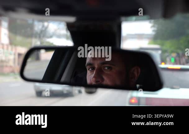 Eyes of male smiling driver reflecting in rearview mirror while riding ...