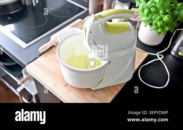 An electric stand mixer whips egg whites into fluffy meringue in a bowl ...